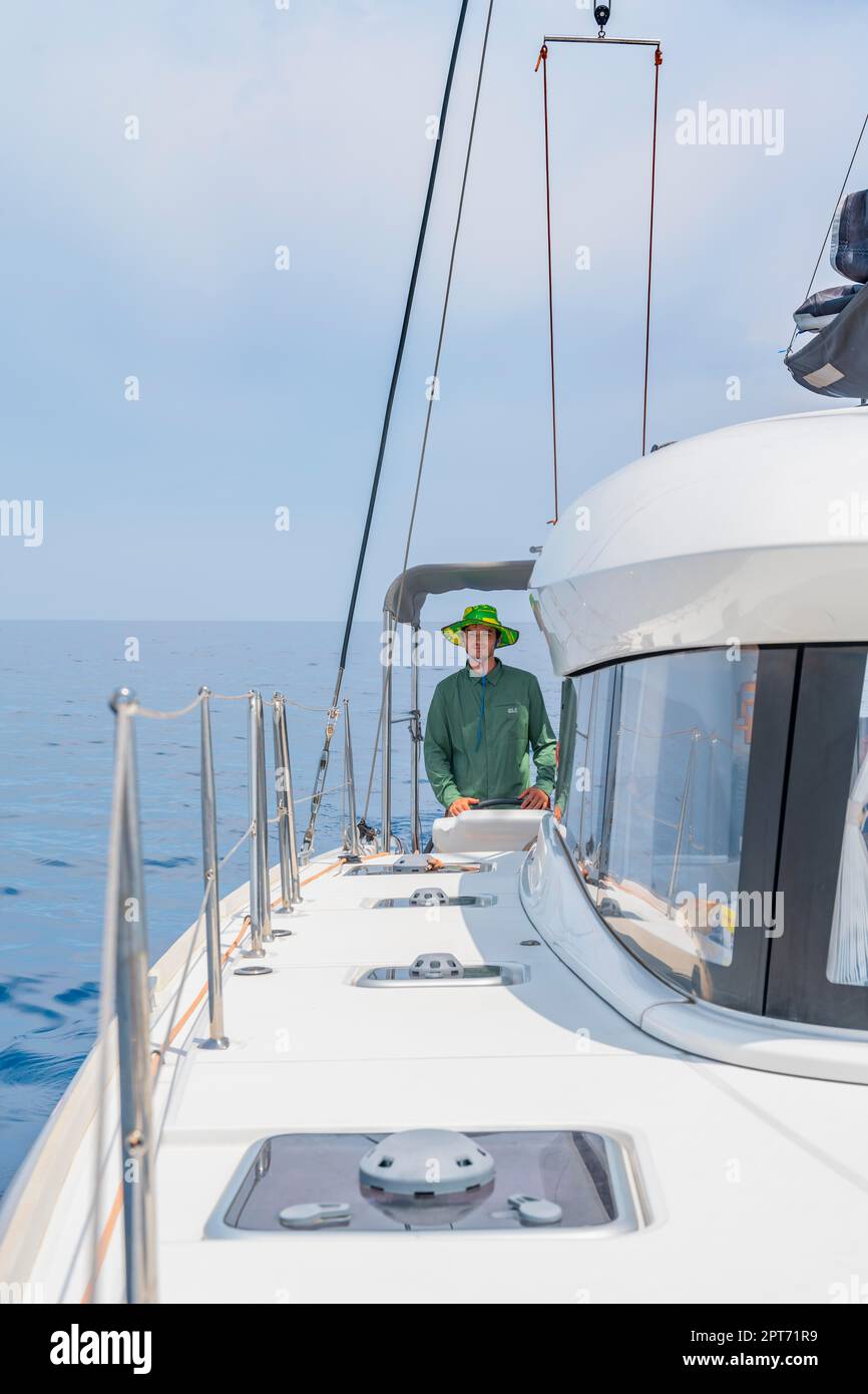 Skipper at the wheel, young man sailing a sailing catamaran, Rhodes ...