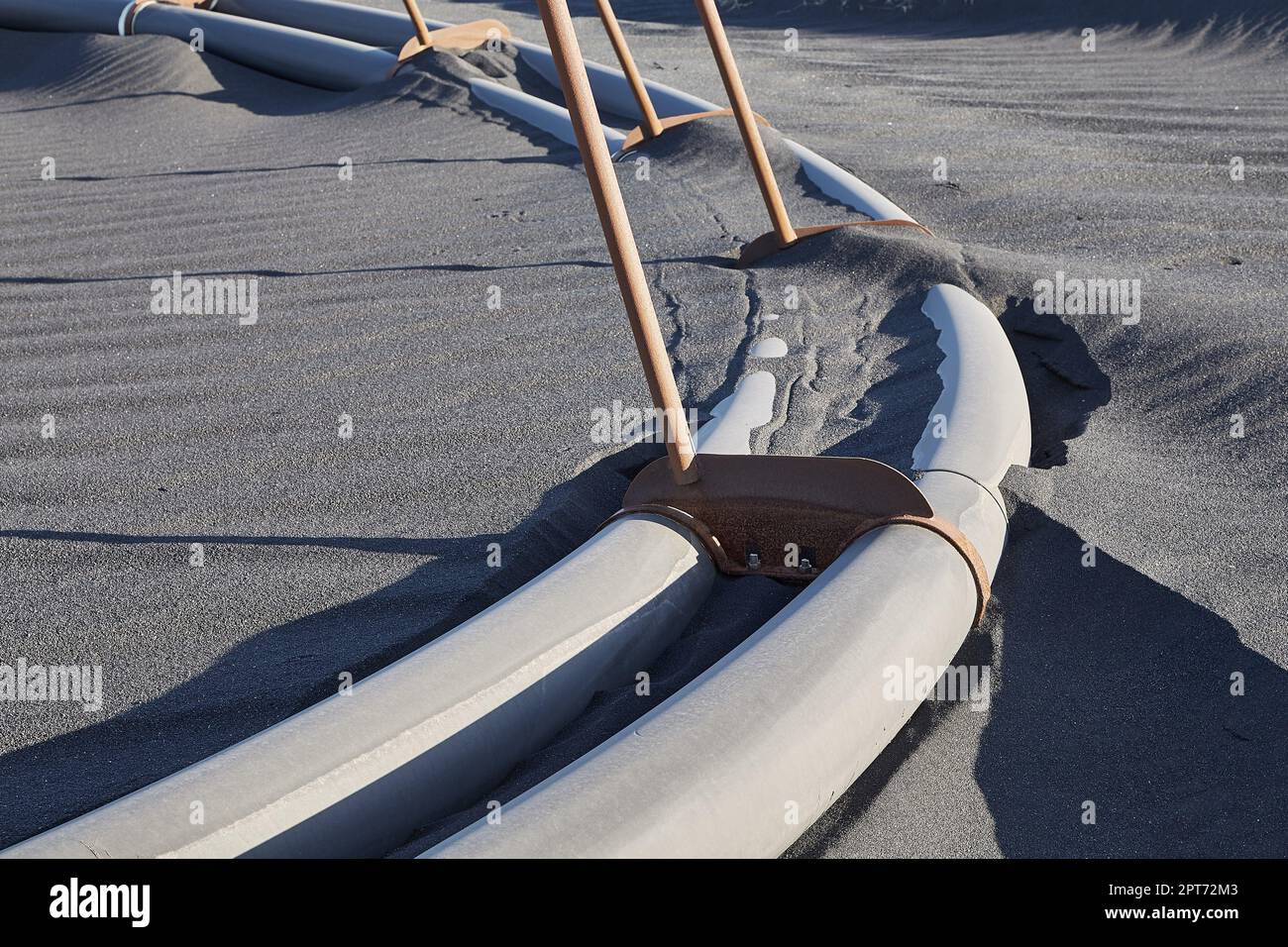 Pipes lying in the black sand of Iceland Stock Photo - Alamy