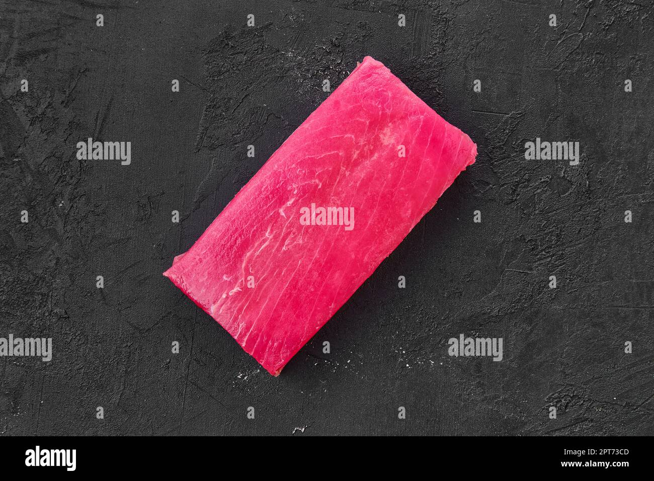 Raw frozen tuna fillet on black background Stock Photo - Alamy