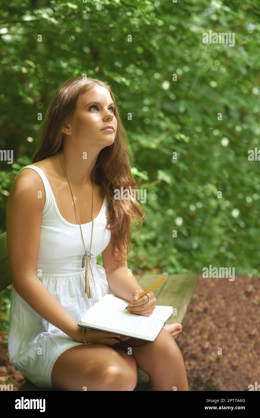Clearing her mind. A beautiful woman sitting in the forest and writing ...