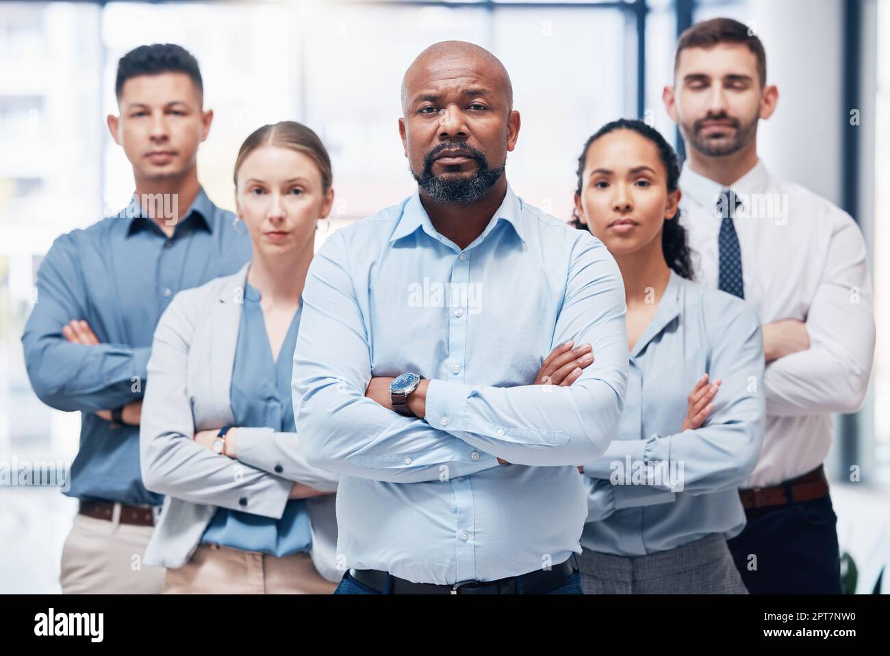 Lined up and ready for action. a group of businesspeople standing with their arms crossed at ...