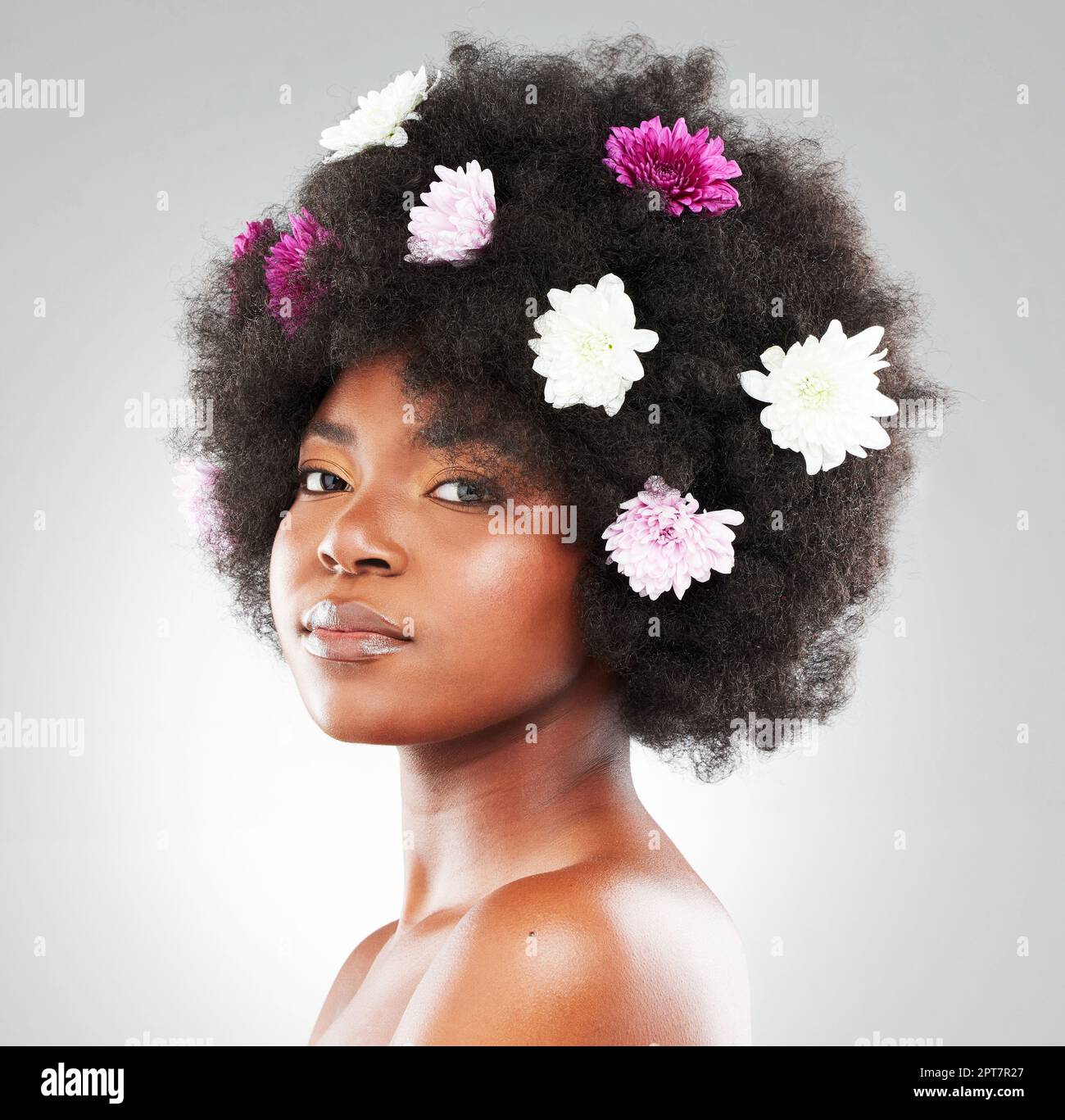 Embracing the flower power. a young woman standing against a grey ...