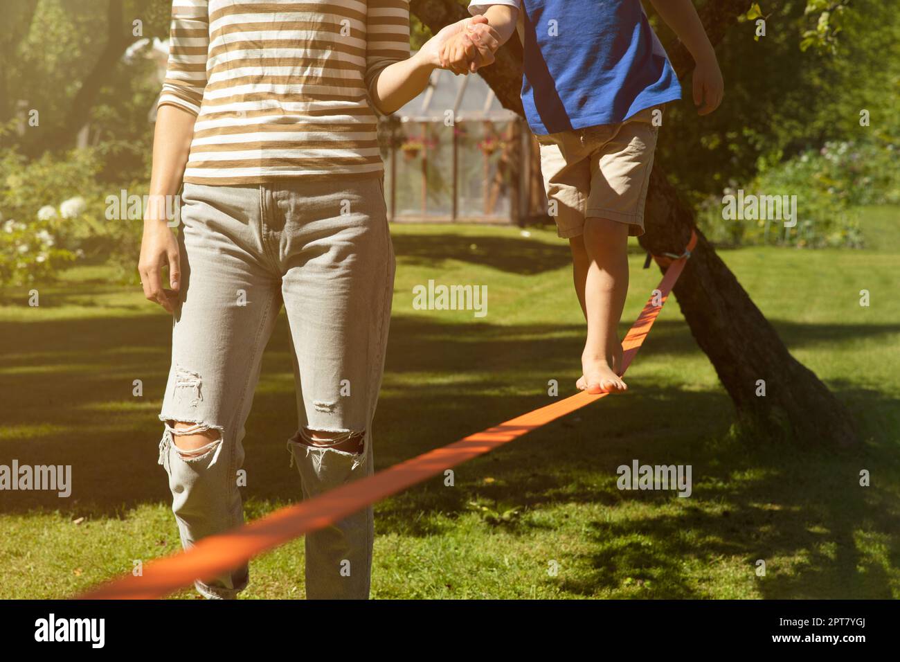 Mother holding kids hand walking on slackline training balance with ...
