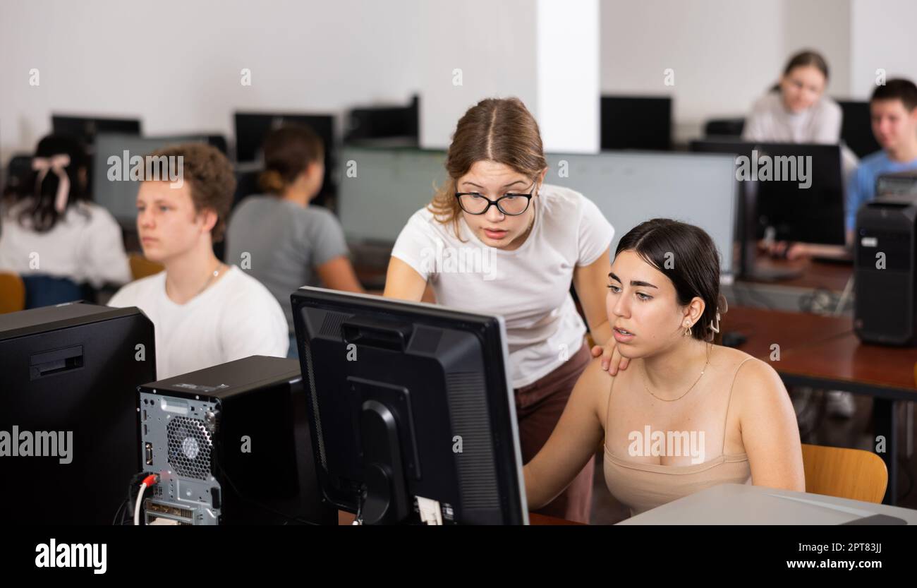 Portrait of young female student helping her female friend studying in ...
