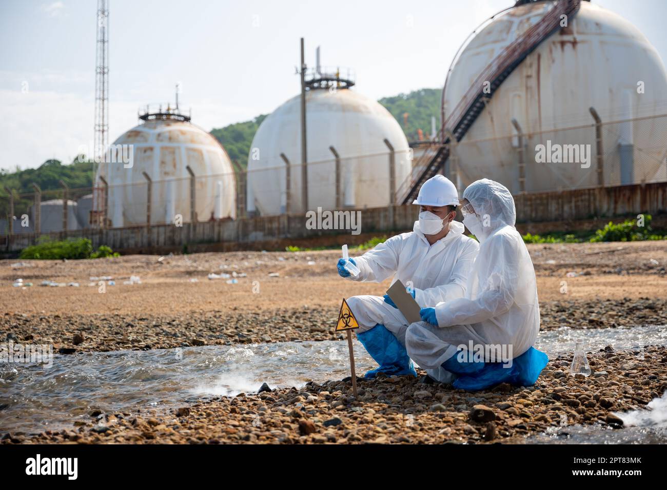 Biologist wear protective suit and mask collects sample of waste water ...