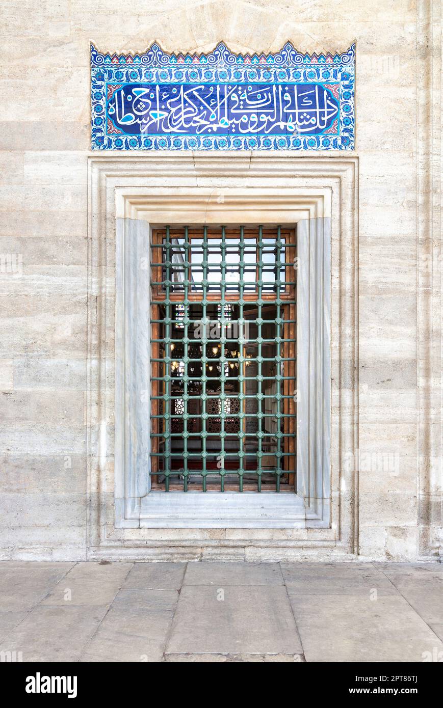 Decorated wrought iron window, in a stone wall, at the courtyard of ...