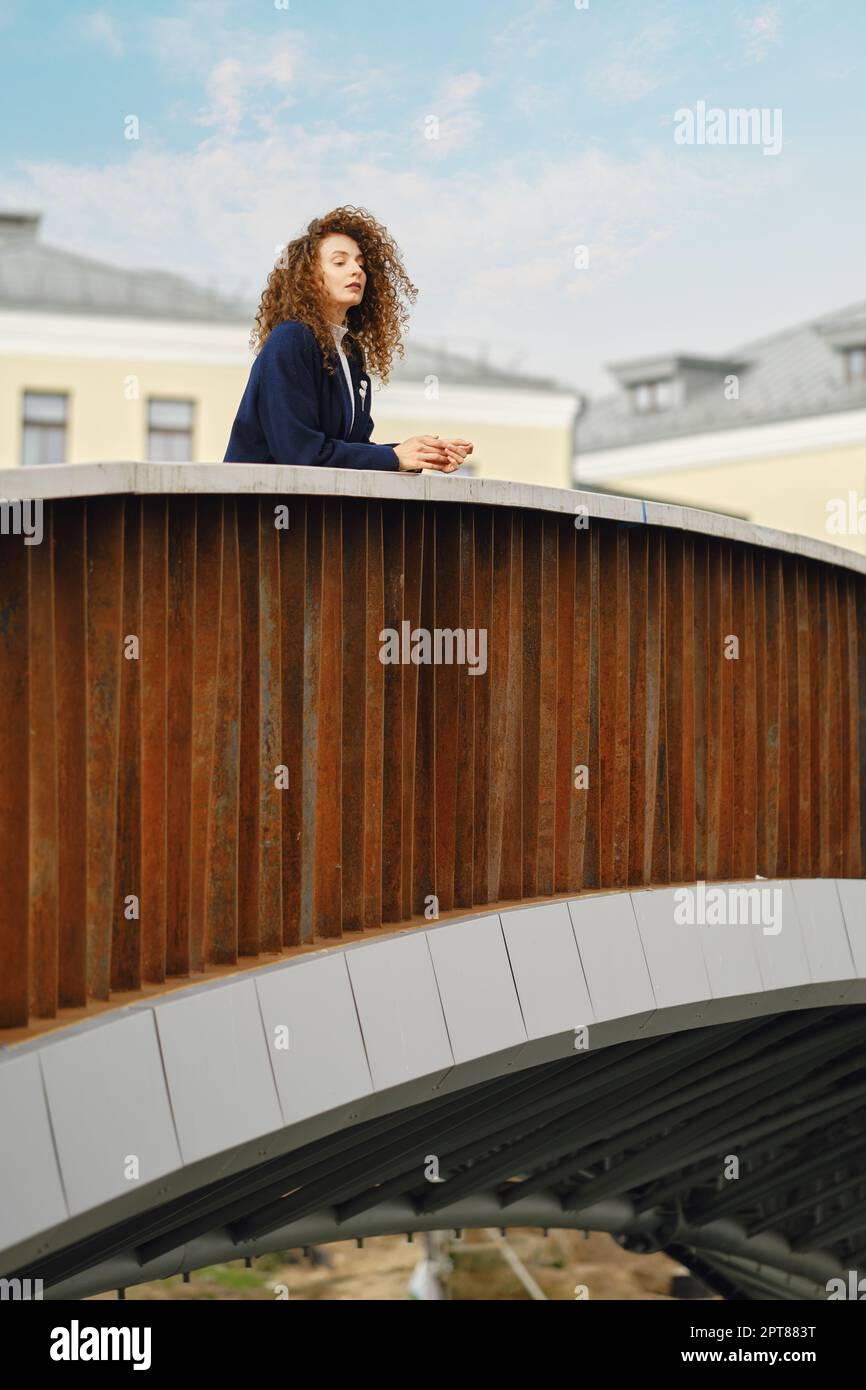 Cute woman leaning against the railing of the foot bridge Stock Photo ...