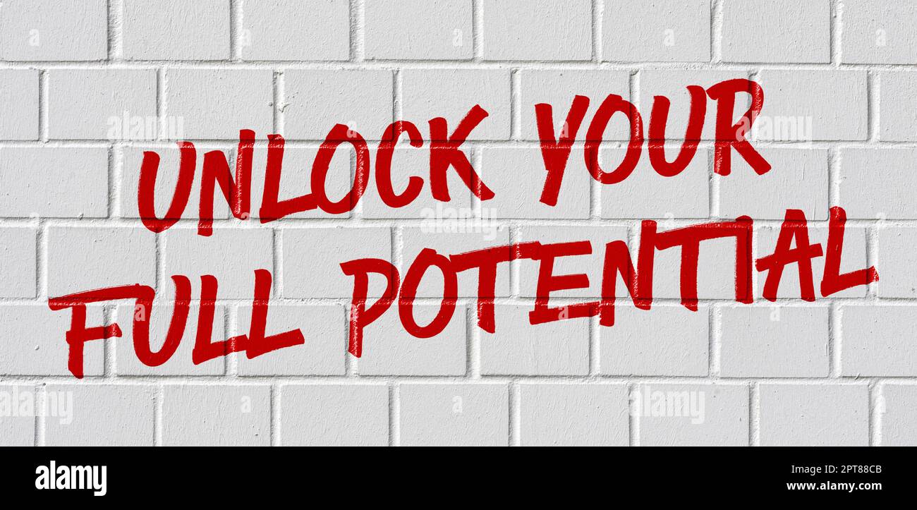 Graffiti on a brick wall - Unlock your full potential Stock Photo - Alamy