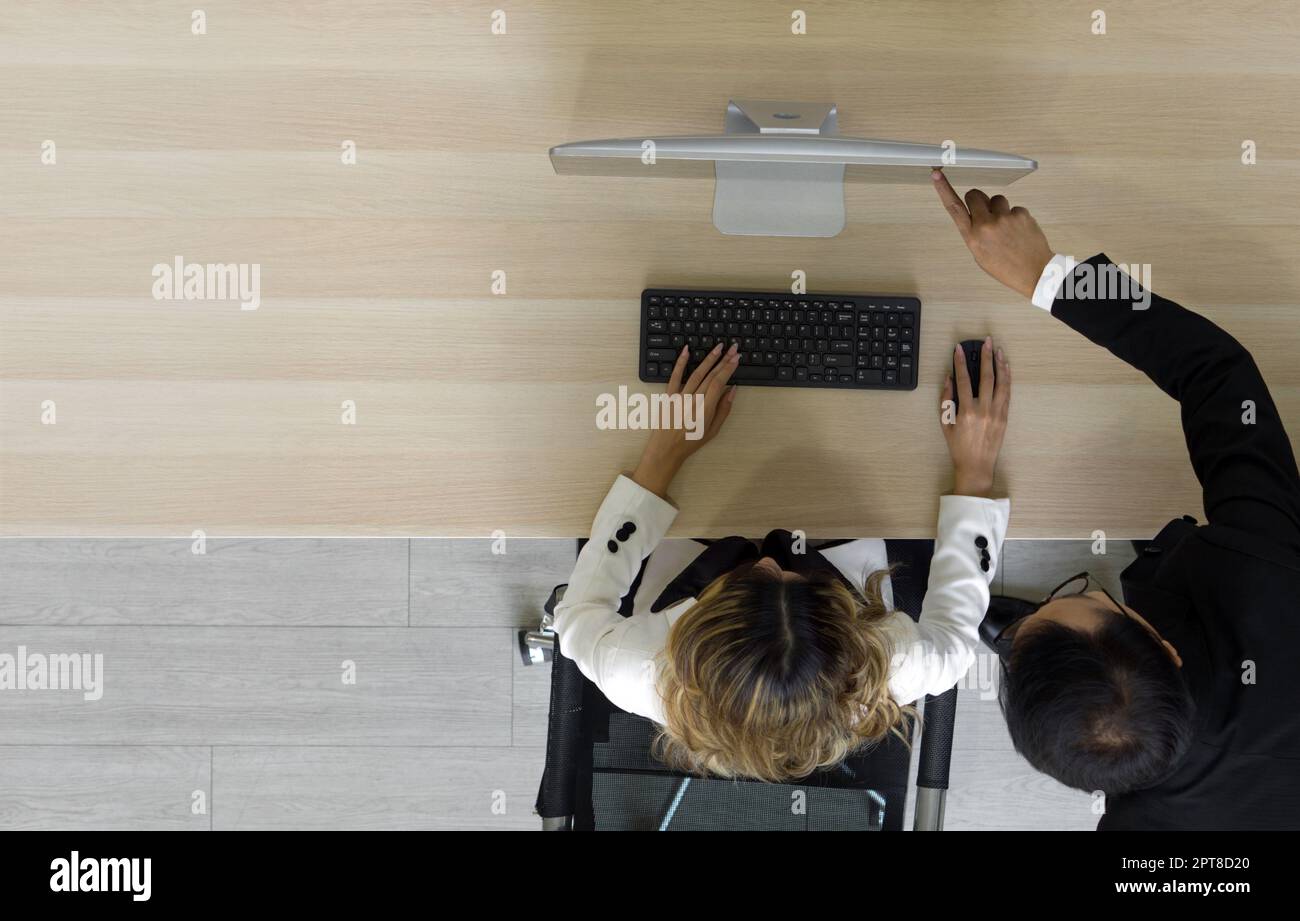 Asian senior manager in black suit pointing finger at computer monitor ...