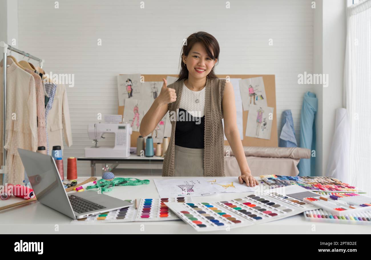 Young dressmaker raise finger thumb up with a smile. Sewing Machine and ...