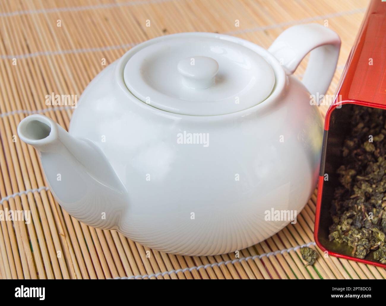 Teapot and a tin of traditional Asian green tea loose Stock Photo - Alamy