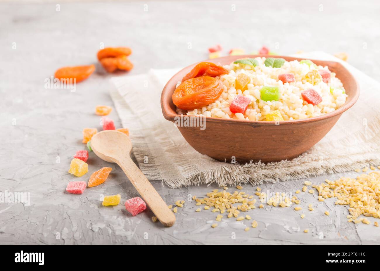 Bulgur porridge with dried apricots and candied fruits in clay bowl on ...