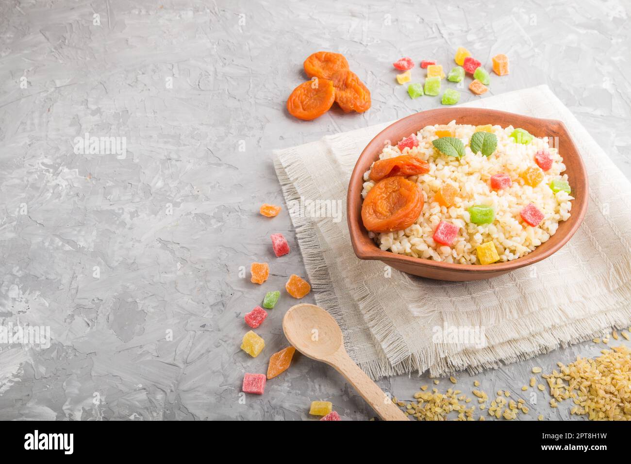 Bulgur porridge with dried apricots and candied fruits in clay bowl on ...