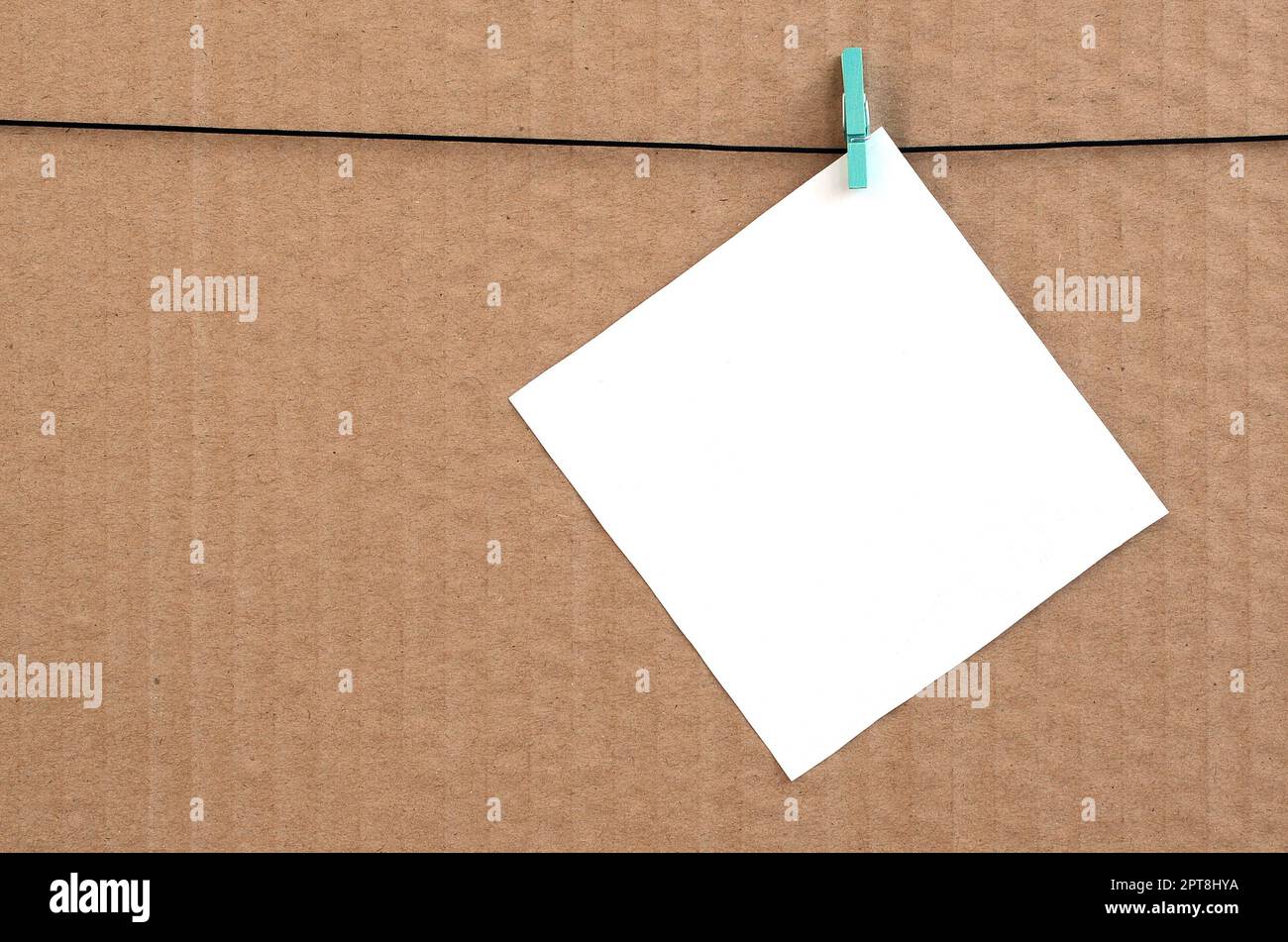 White blank card on rope on a brown cardboard background. Creative ...