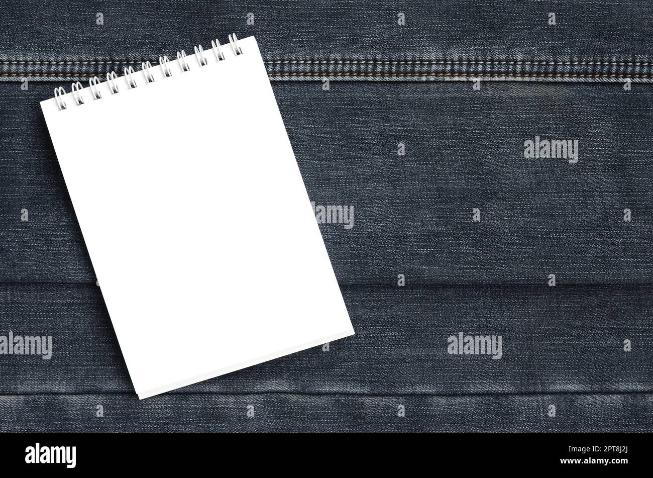 White notebook with clean pages lying on dark blue jeans background ...