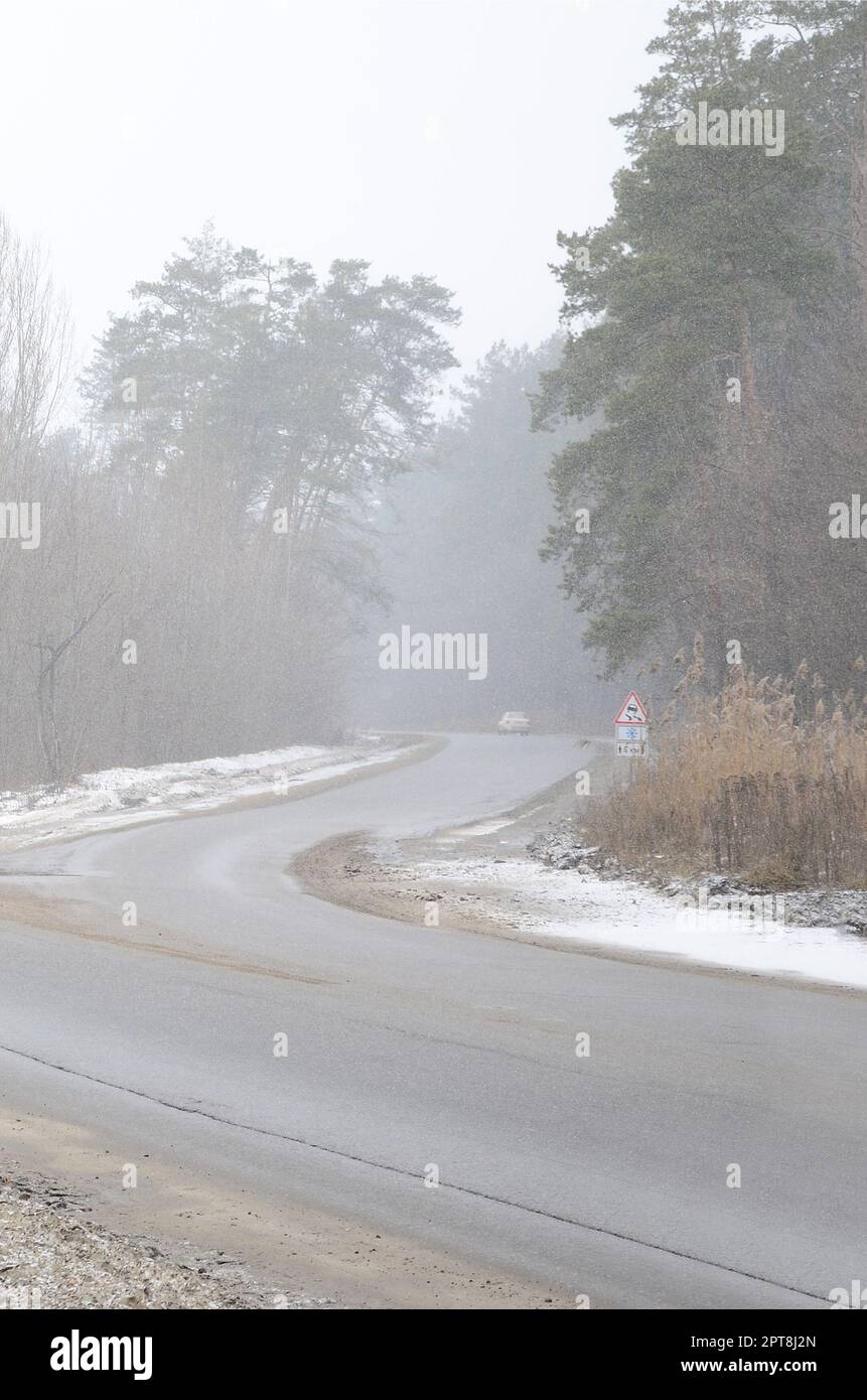 Crossroads on a suburban asphalt road in wintertime during a blizzard ...