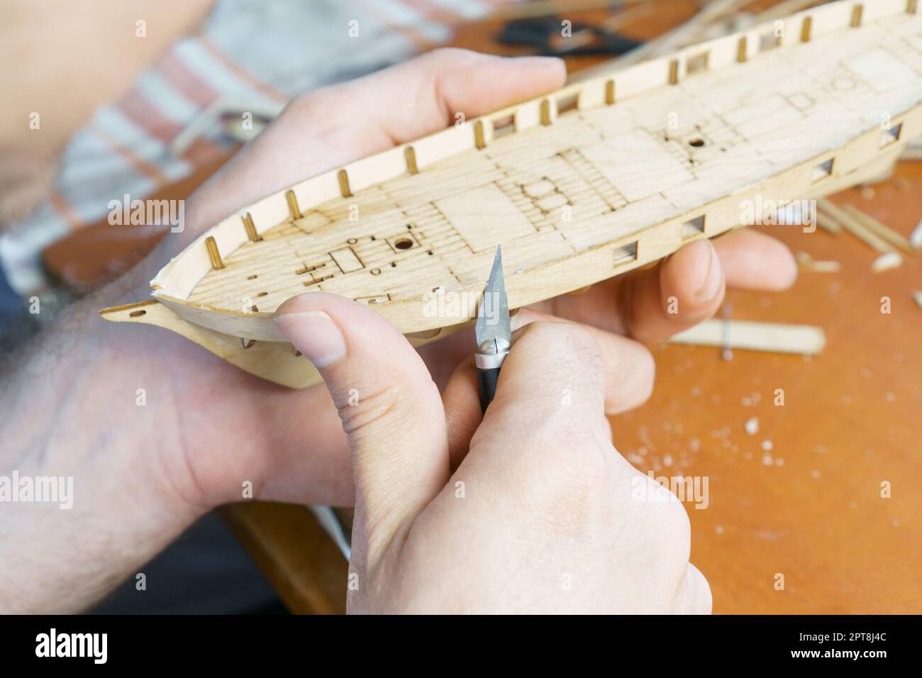 Hands of man cutting out details for ship model with clerical knife ...