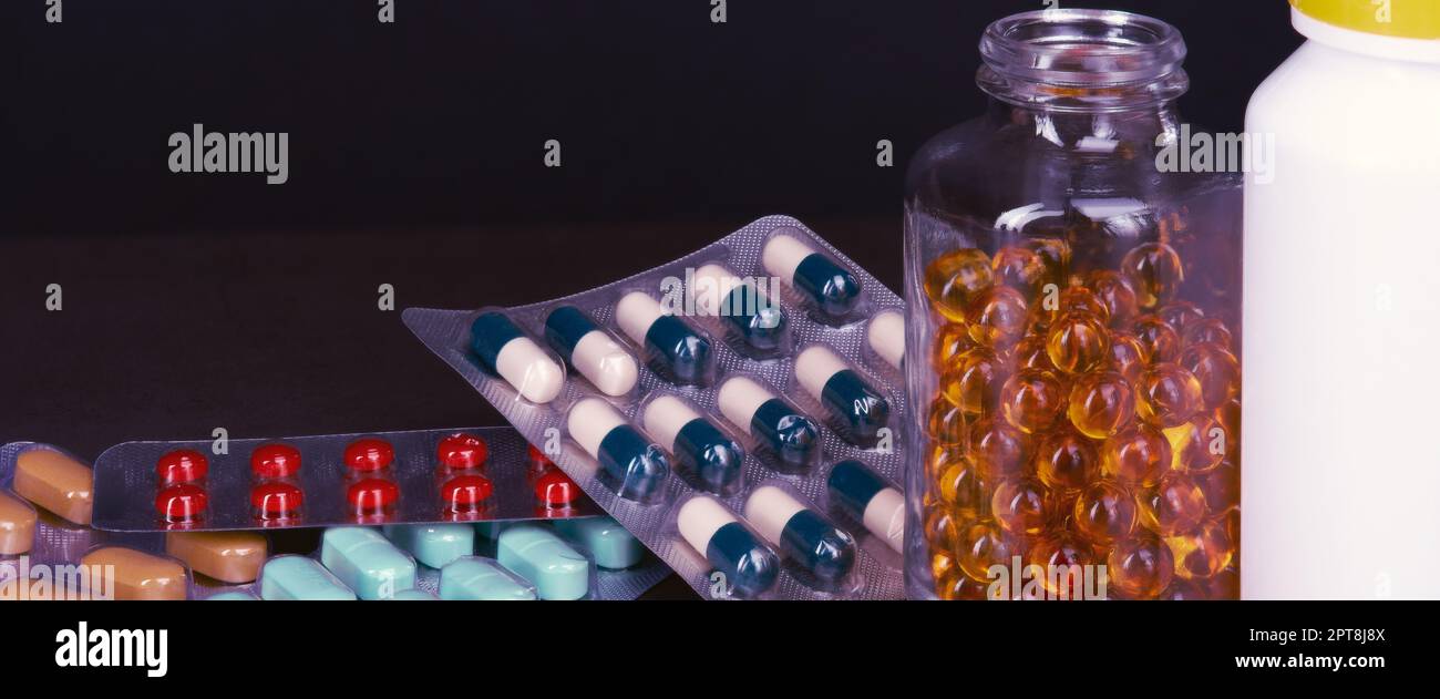 Pills and tablets of different colors are scattered and in bottles on a ...