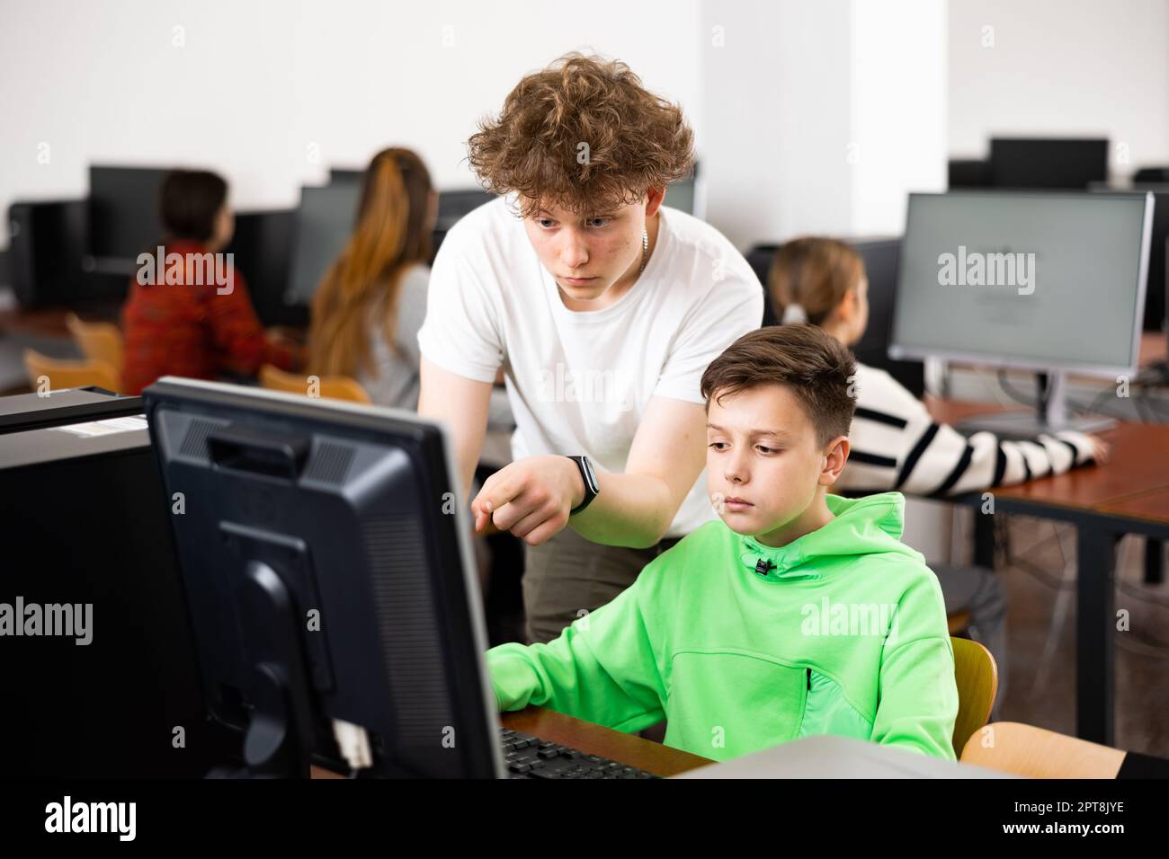 Teenage boy helping young boy with PC problem in computer class Stock ...