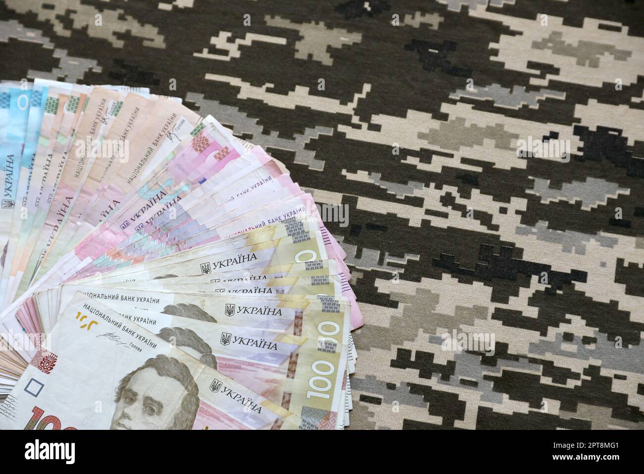 Ukrainian hryvnya bills on fabric with texture of Ukrainian military ...