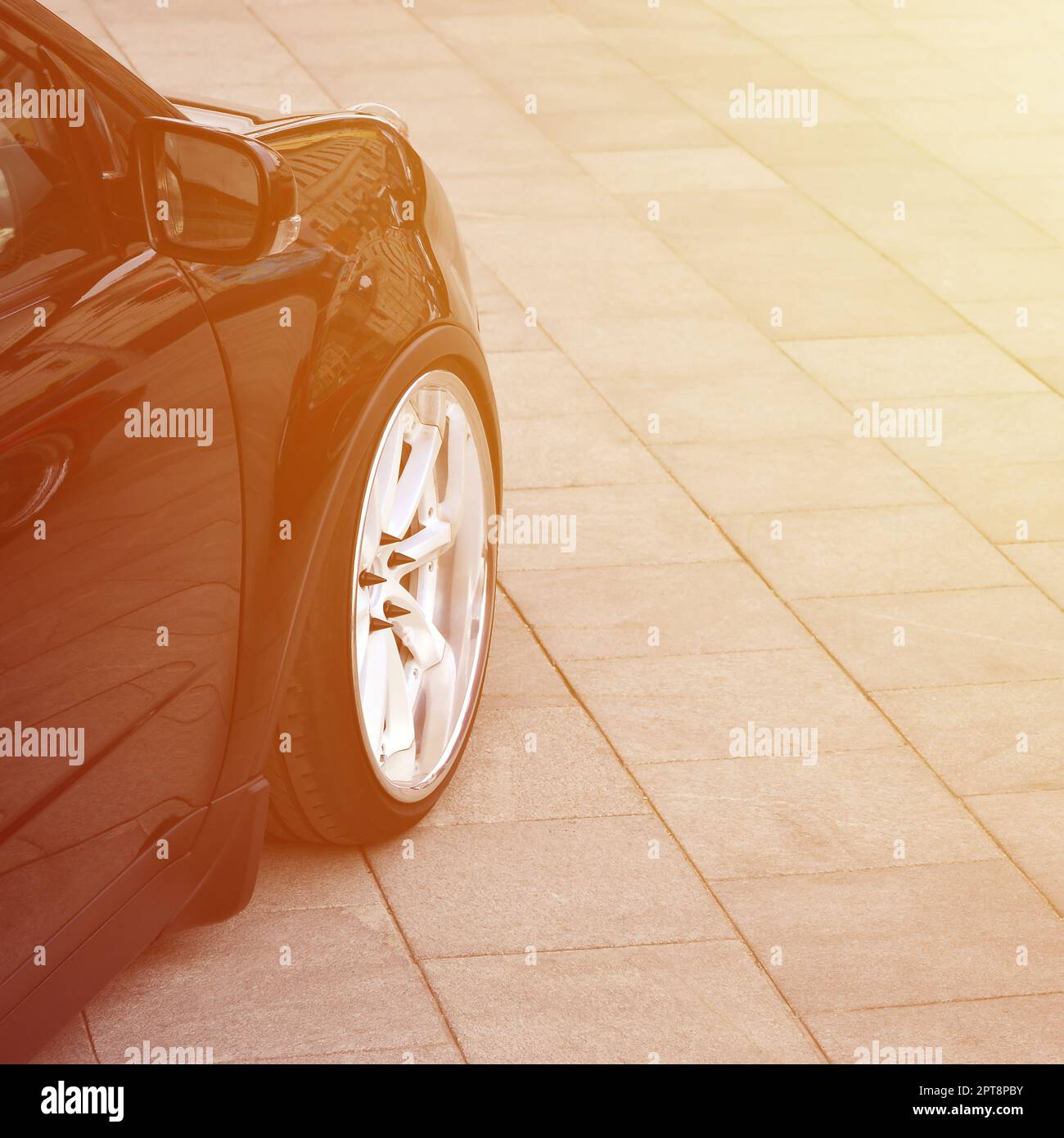 Diagonal view of a black glossy car with white wheels, which stands on ...
