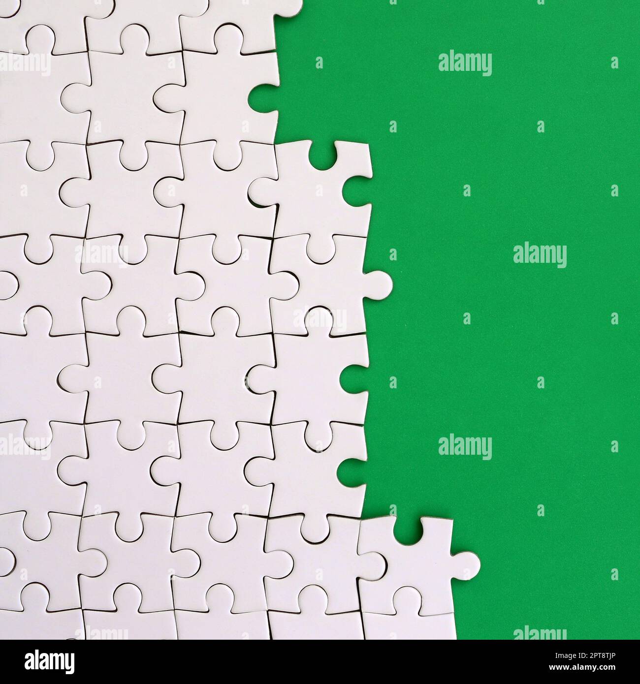 Fragment of a folded white jigsaw puzzle on the background of a green ...