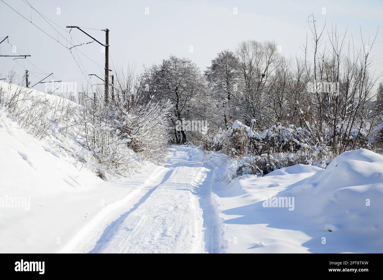 The road that lies parallel to the railway line is covered with snow on a sunny day after a ...