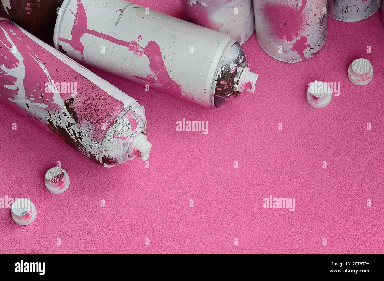 Some used pink aerosol spray cans and nozzles with paint drips lies on ...