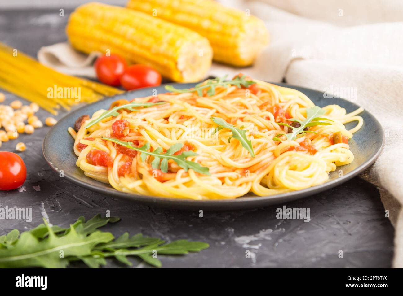 Corn noodles with tomato sauce and arugula on a black concrete ...