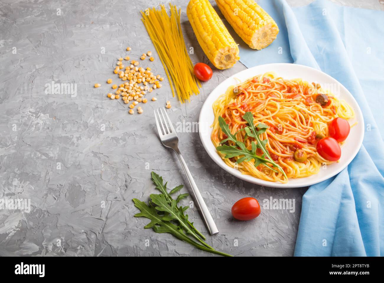 Corn noodles with tomato sauce and arugula on a gray concrete ...