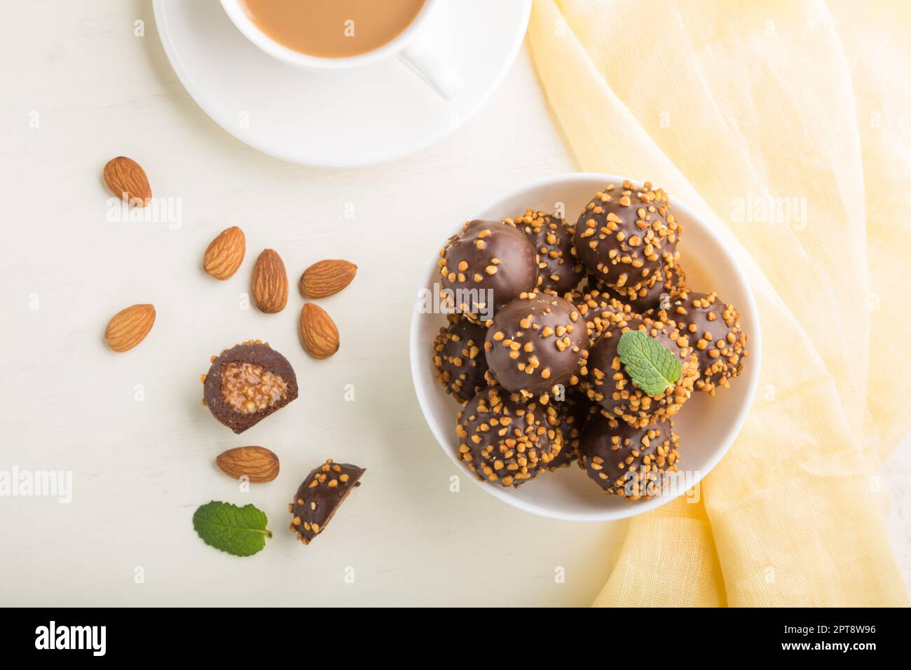 Chocolate caramel ball candies with almonds and a cup of coffee on a ...