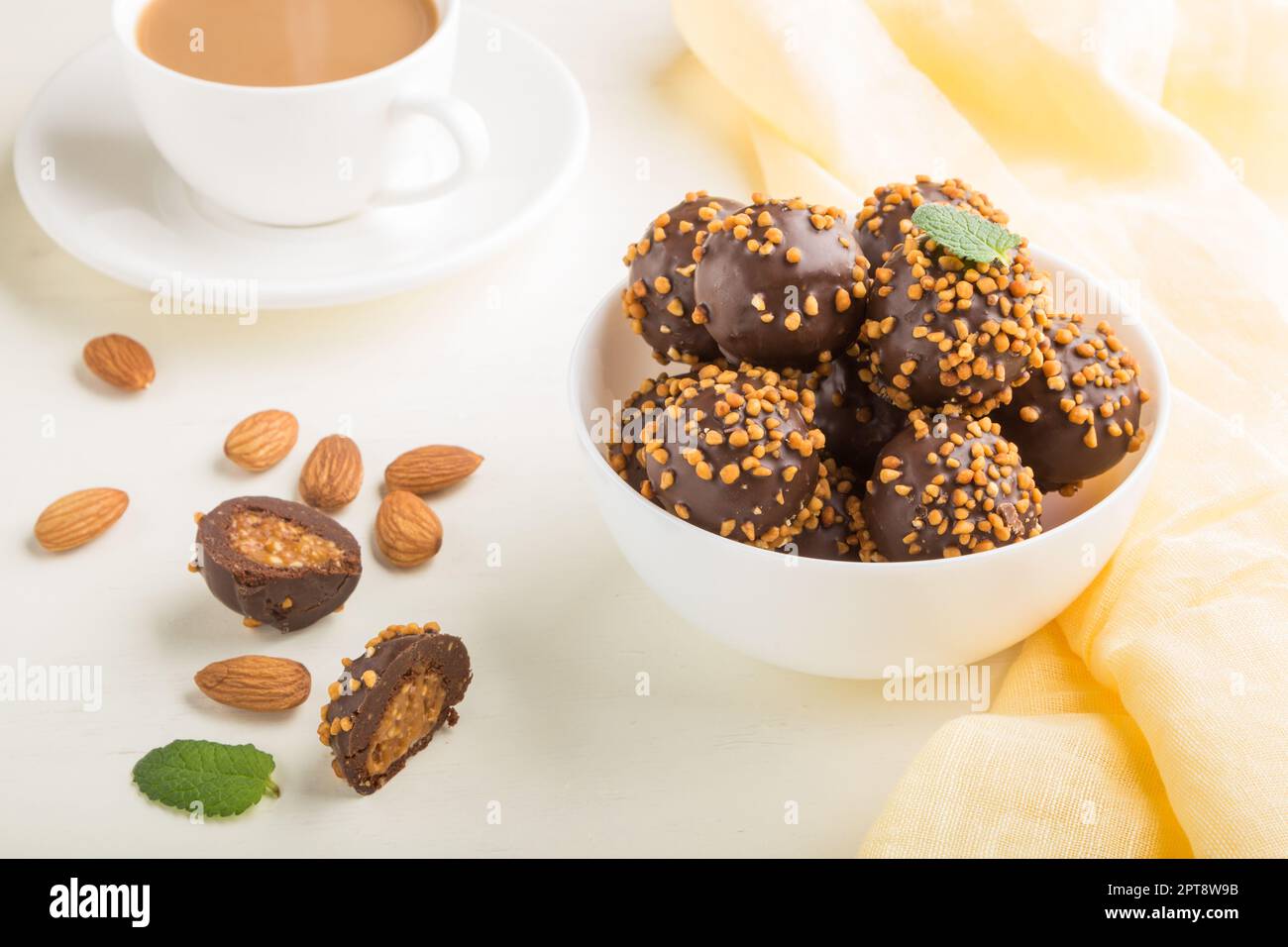 Chocolate caramel ball candies with almonds and a cup of coffee on a ...