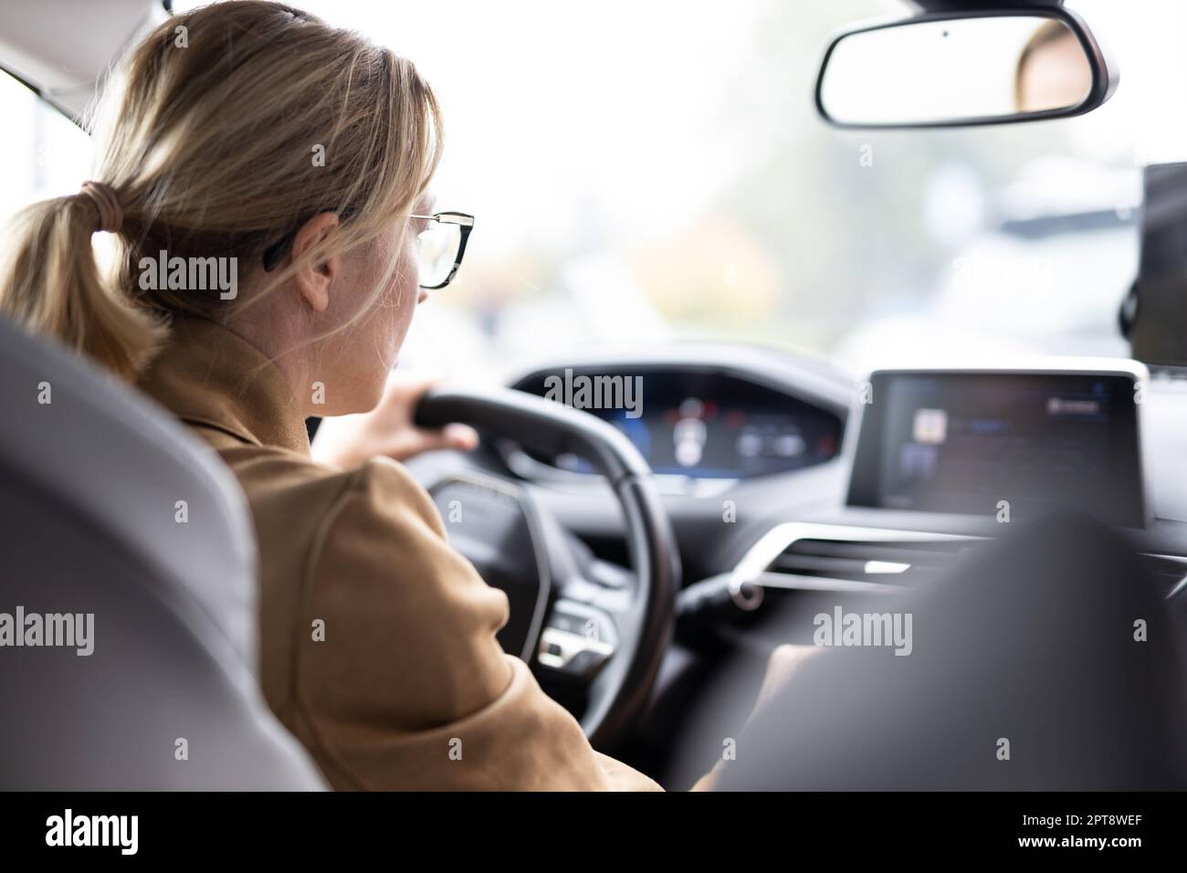 Business woman driving a car to work. Female driver steering car on the ...