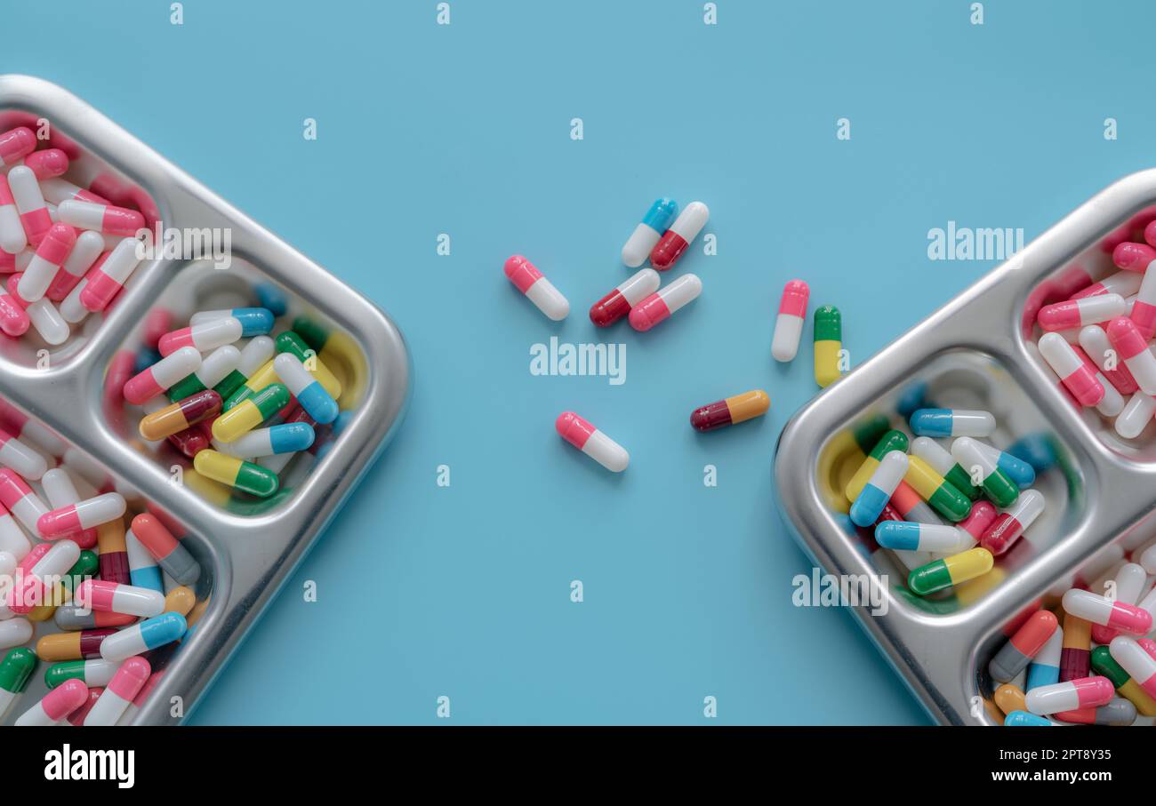 Multi-colored antibiotic capsule pill on tray and blue background. Antibiotic drug resistance ...