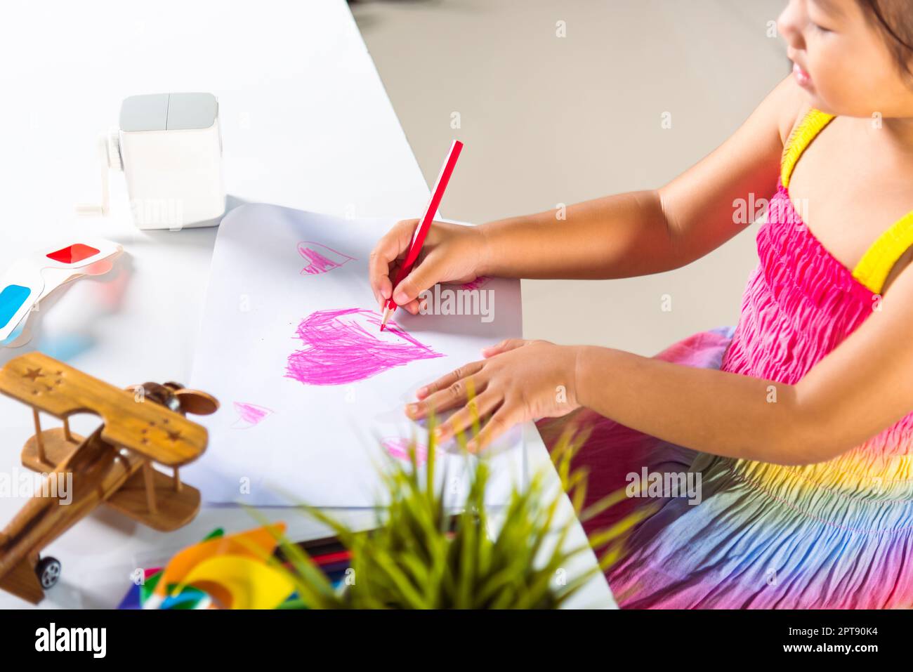 Happy child little girl colorful drawing pink heart on white paper ...