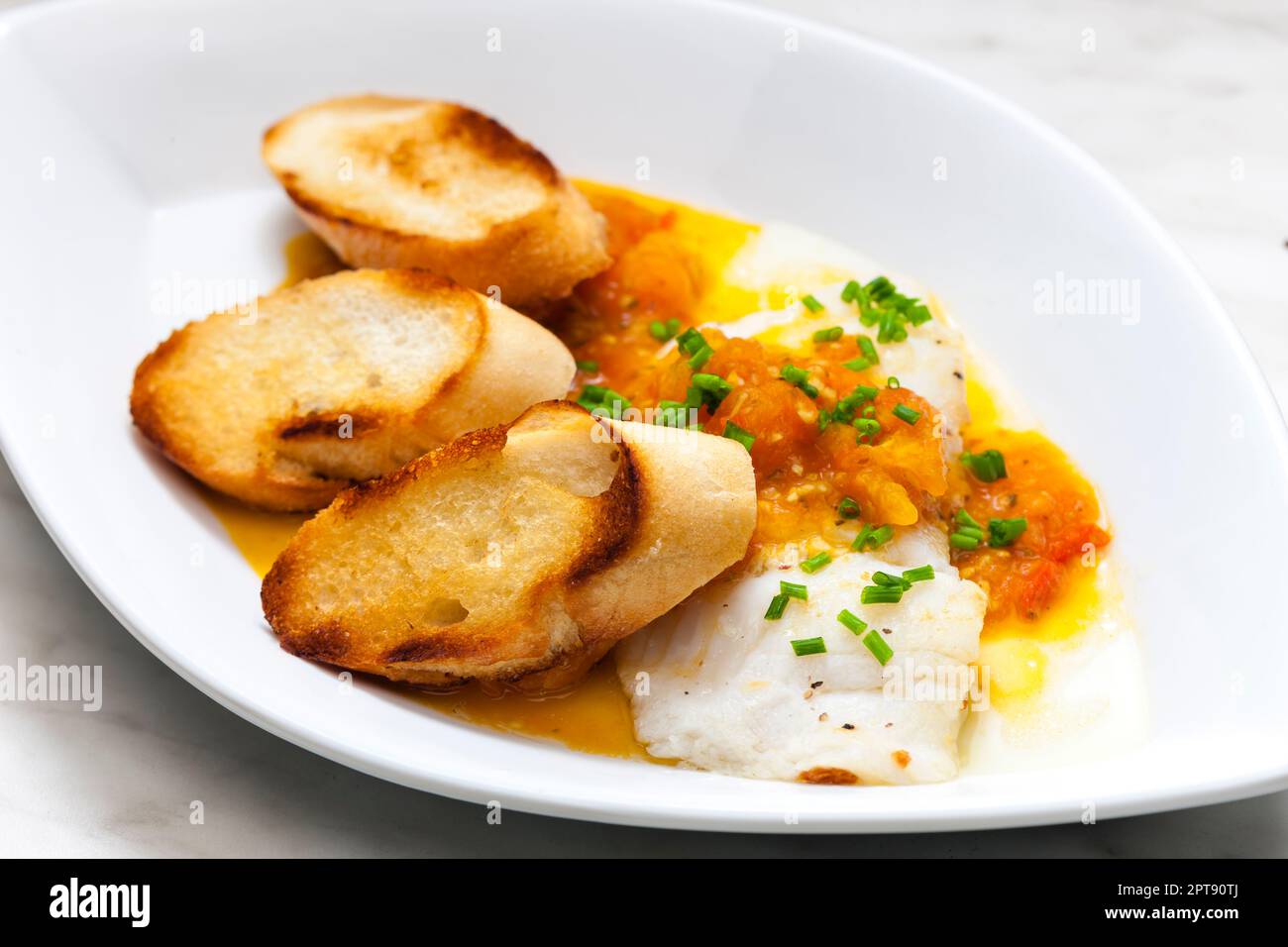 white fish with tomato sauce and roasted baguette slices Stock Photo ...