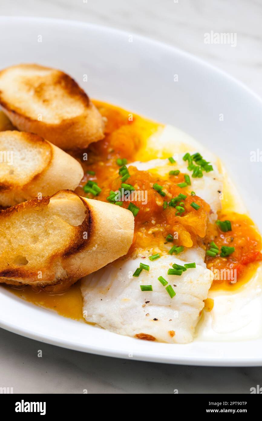 white fish with tomato sauce and roasted baguette slices Stock Photo ...