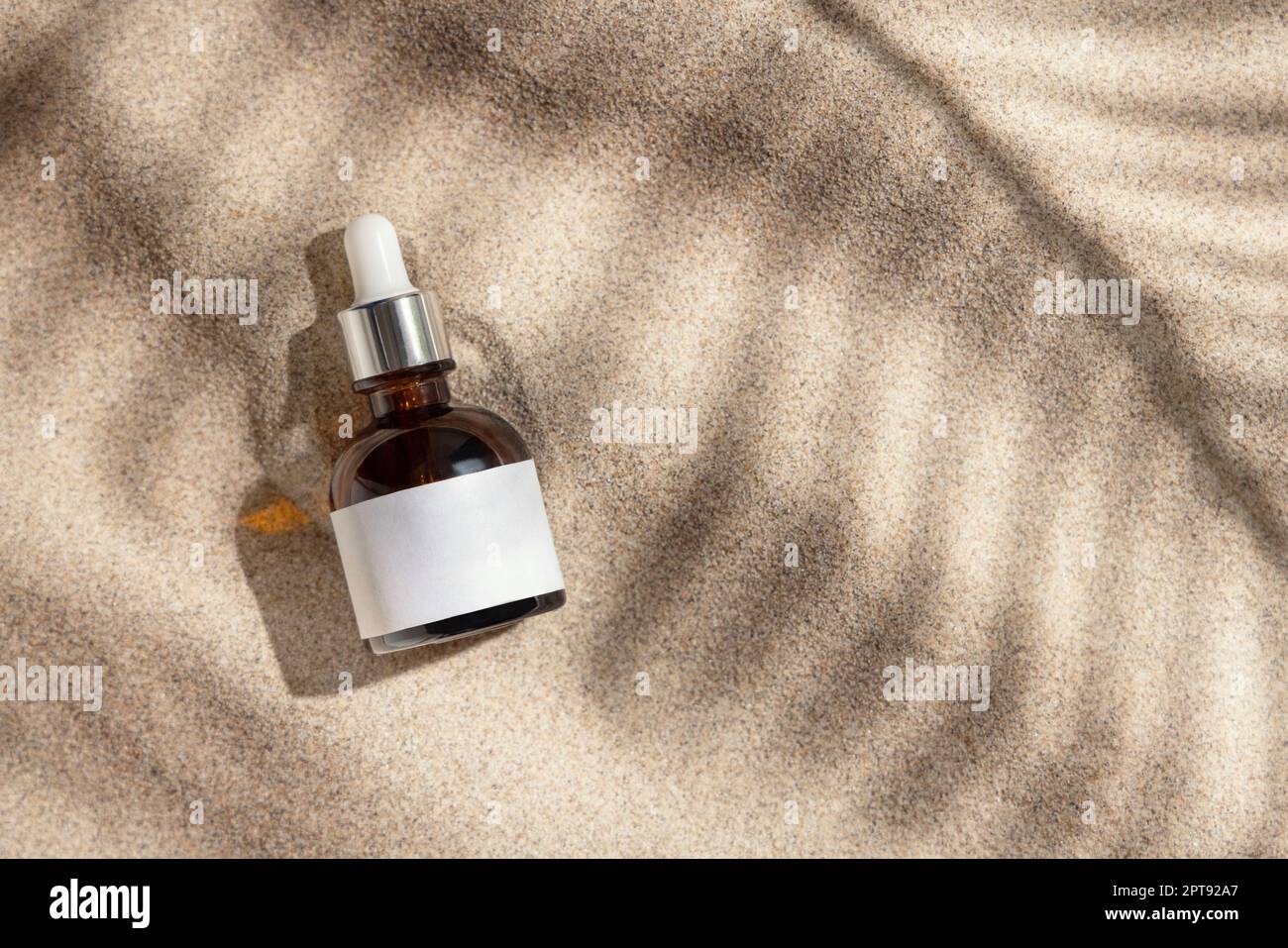 Dropper spray bottle with blank label on beige sand top view. Packaging ...