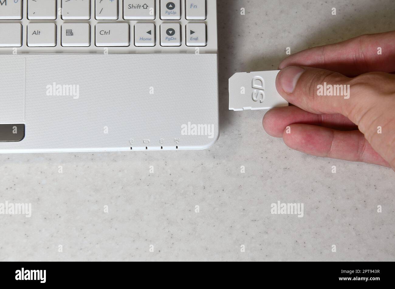 A male hand inserts a white compact SD card into the corresponding ... A male hand inserts a white compact SD card into the corresponding ...