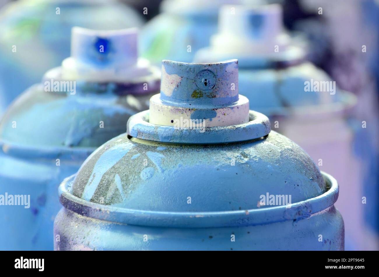A lot of dirty and used aerosol cans of bright blue paint. Macro ...