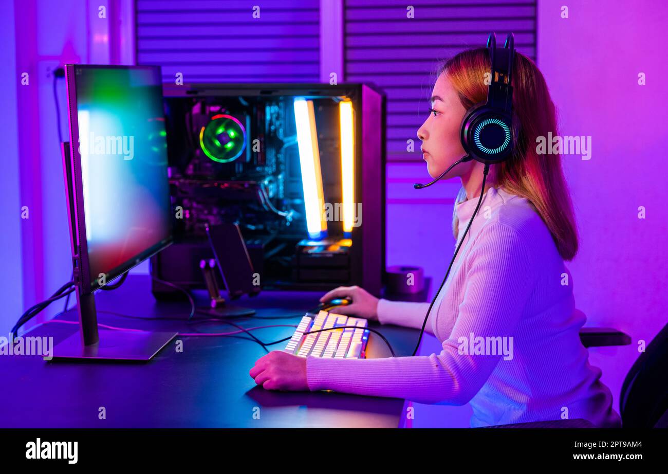 Asian professional gamer playing online video game on desktop computer ...