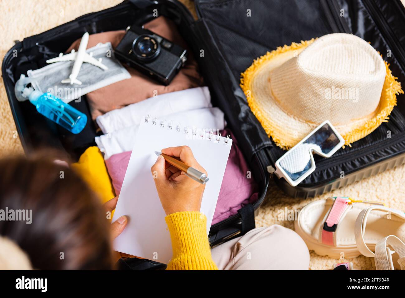Making check list of things to pack for travel. Woman writing paper ...