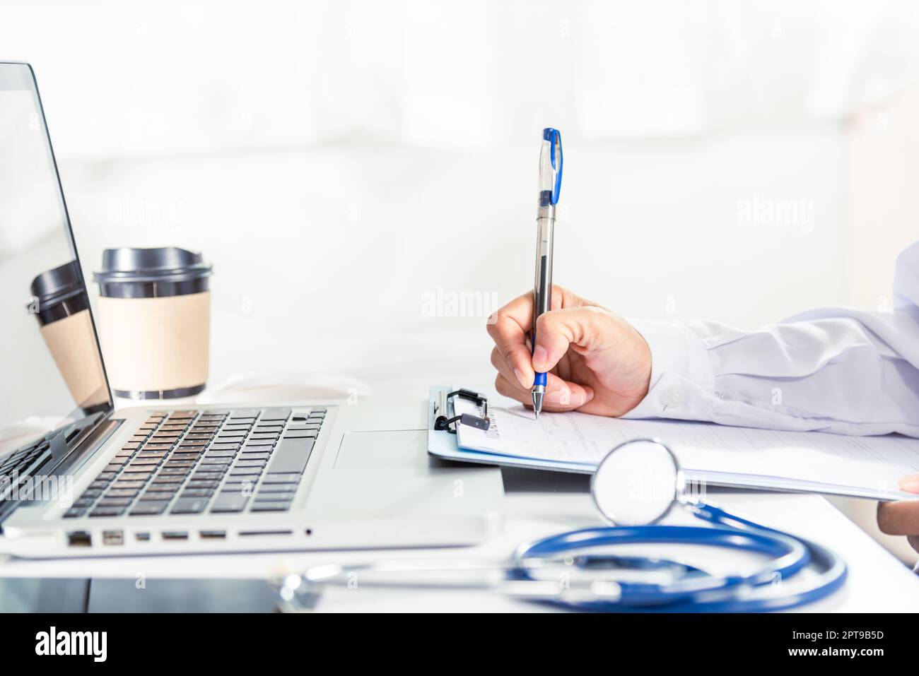 Doctor or nurse in uniform with stethoscope writing something ...