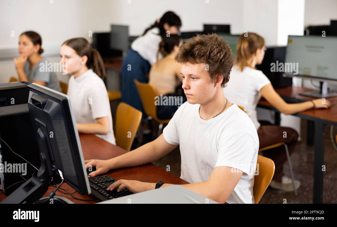 Smart male teen learning computer science while she is using a PC in ...