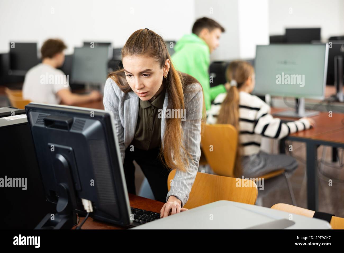 Teacher using personal computer during lesson in school Stock Photo - Alamy