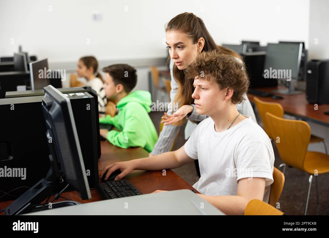 Teacher explaining task solution to pupil during computer science ...