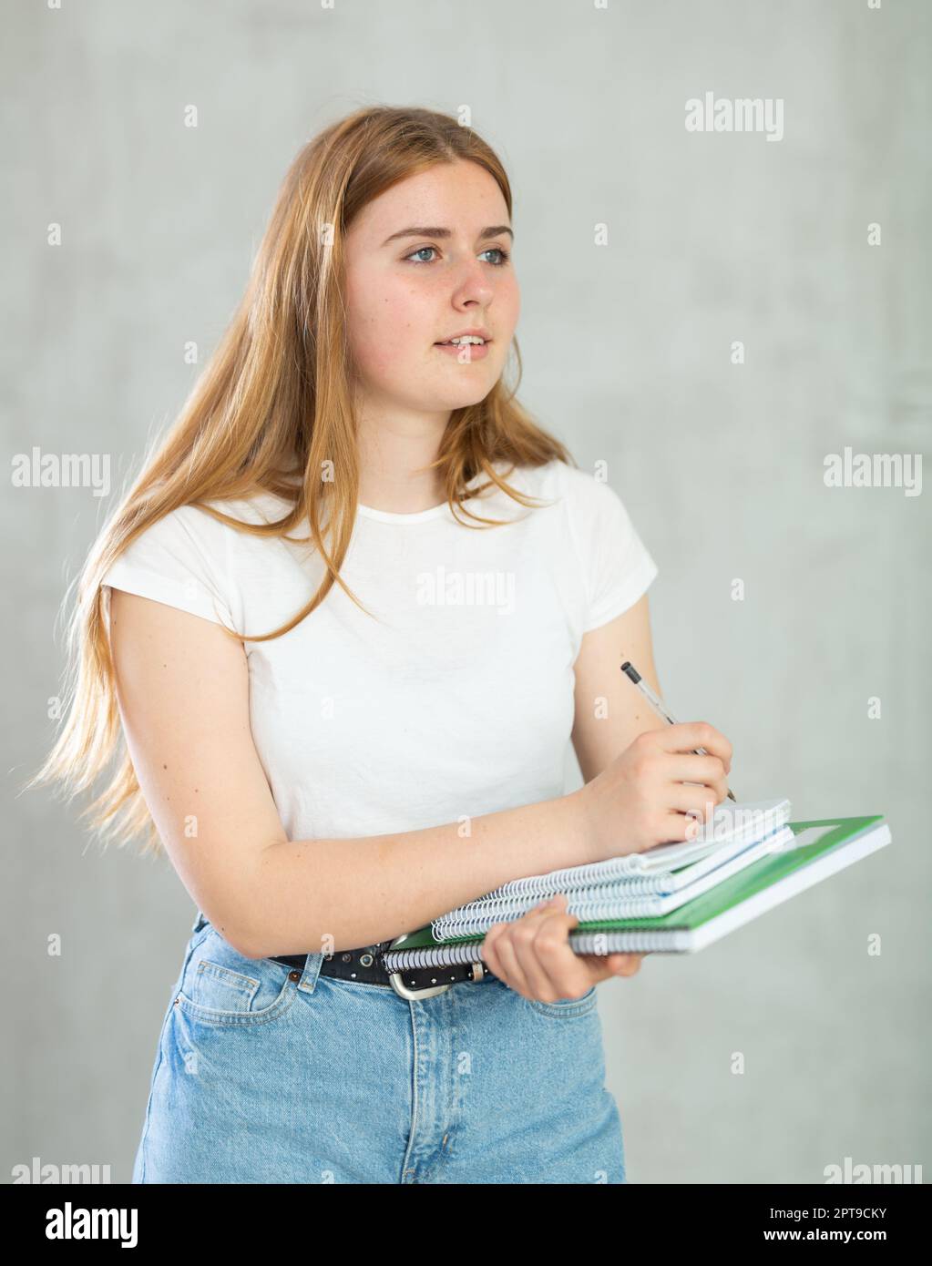 Positive girl student makes notes in notebook. Education in high school ...