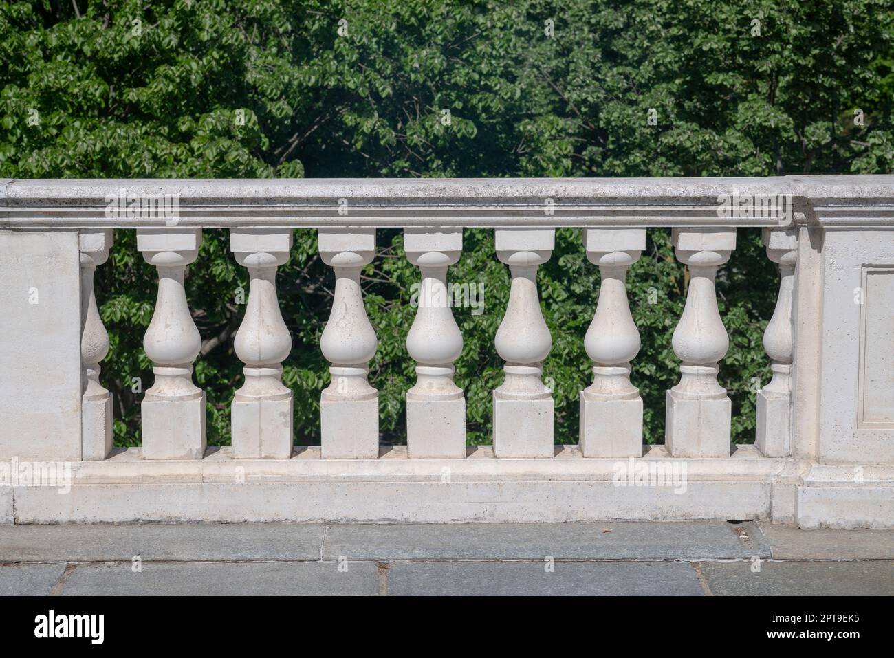 park with a white marble balustrade in the background green plants give ...