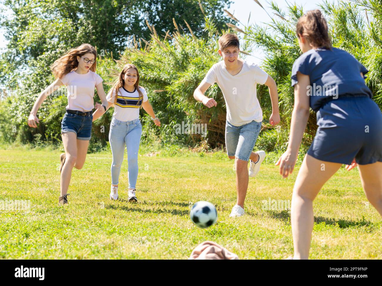 Company of glad teenagers playing football Stock Photo - Alamy