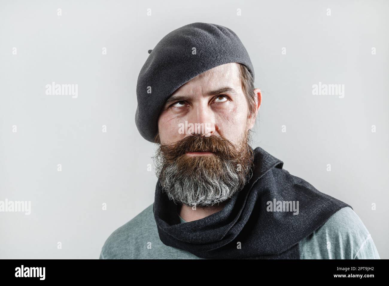 Bearded man in gray beret with scarf. Studio portrait on a light ...